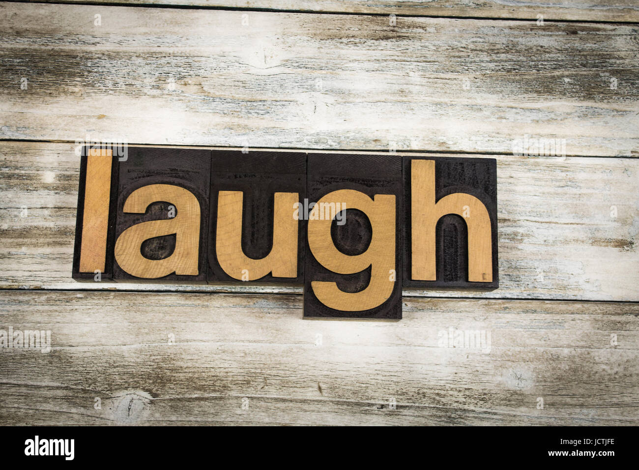 The word "Laugh" written in wooden letterpress type on a white washed ...
