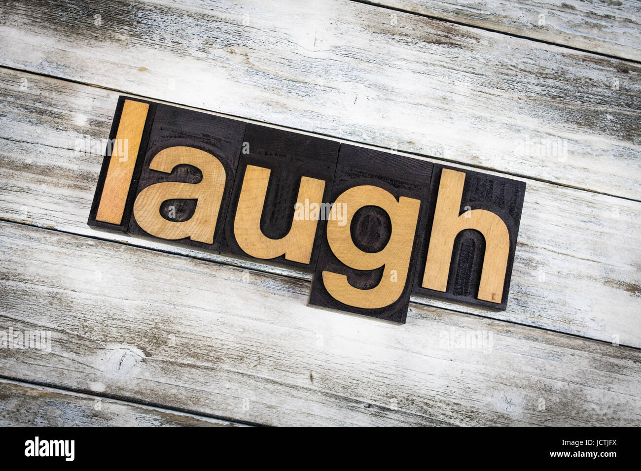 The word "Laugh" written in wooden letterpress type on a white washed ...