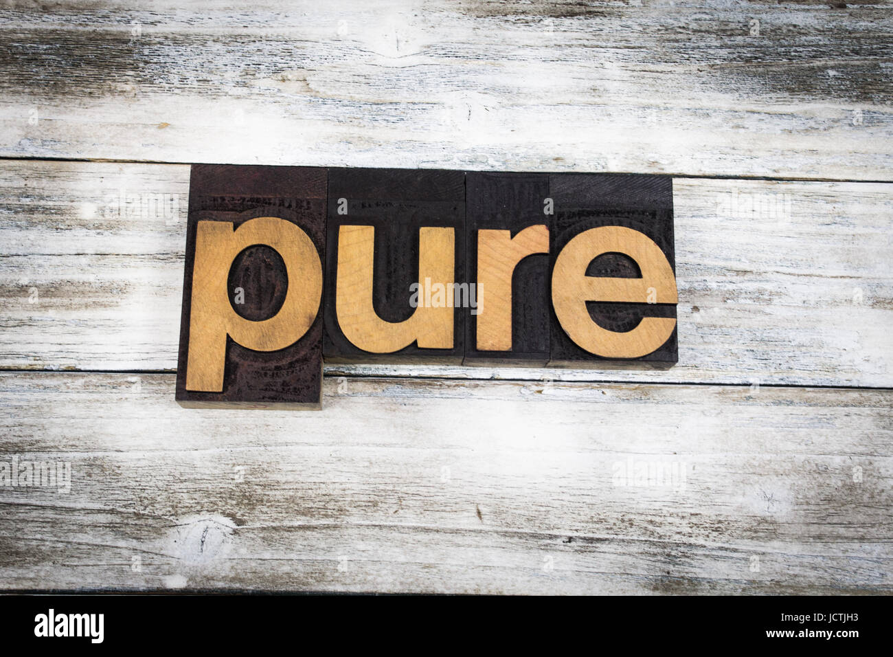 The word "pure" written in wooden letterpress type on a white washed ...