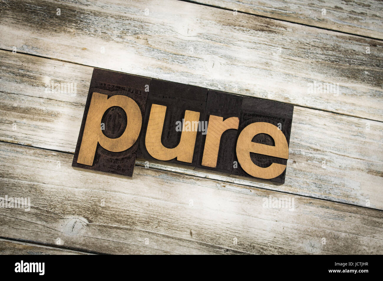 The word "pure" written in wooden letterpress type on a white washed ...