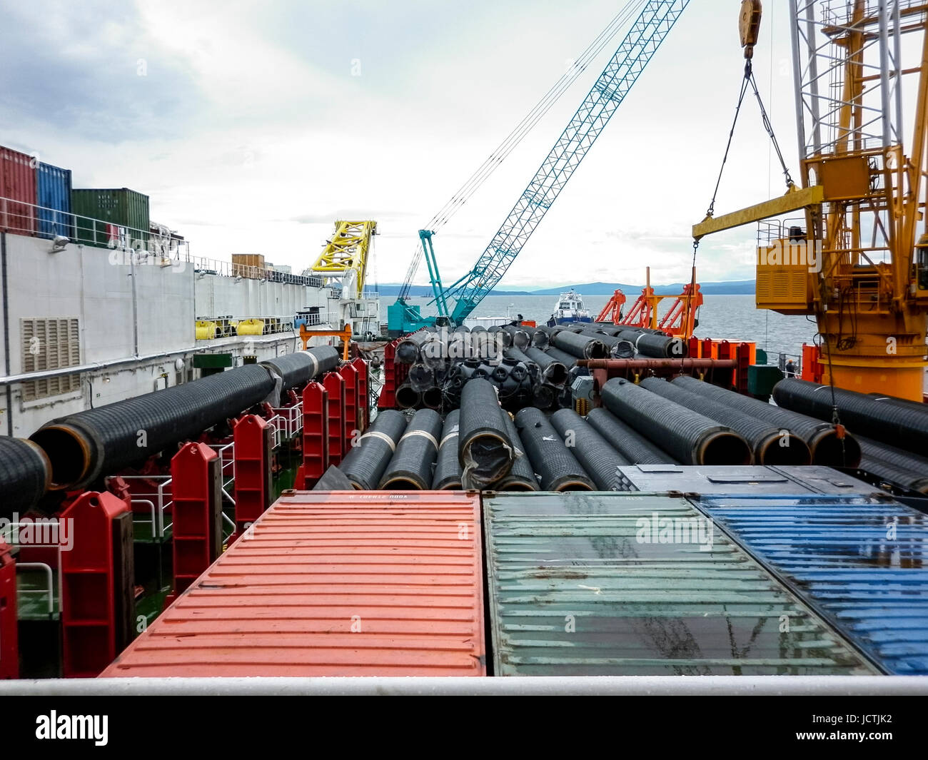 The deck lay barge. Pipes and Lifting cranes on the ship. Equipment for ...