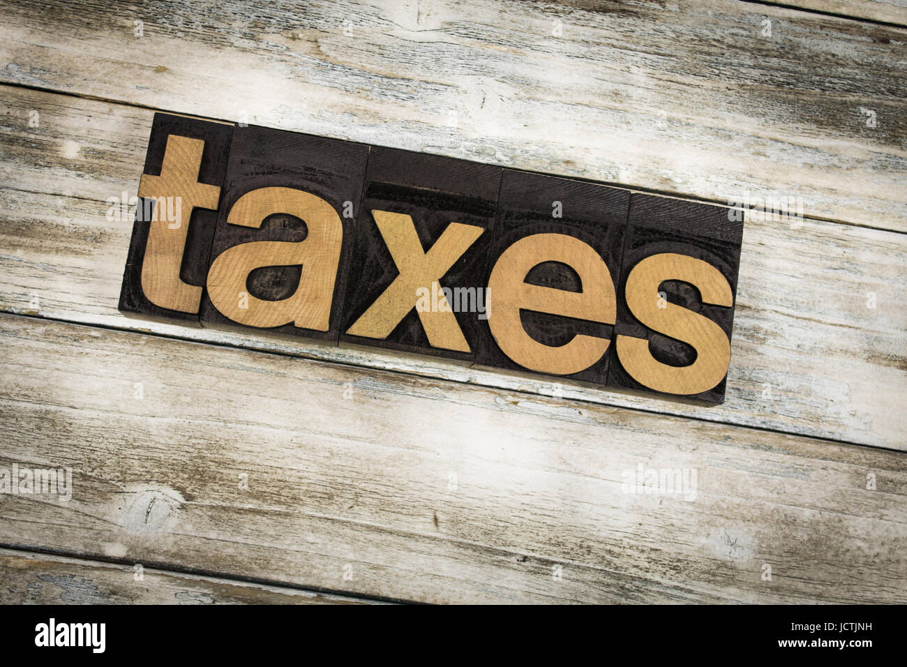 The word "taxes" written in wooden letterpress type on a white washed ...
