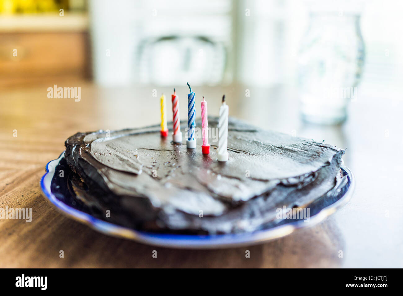Simple square small chocolate birthday cake with five colorful candles ...