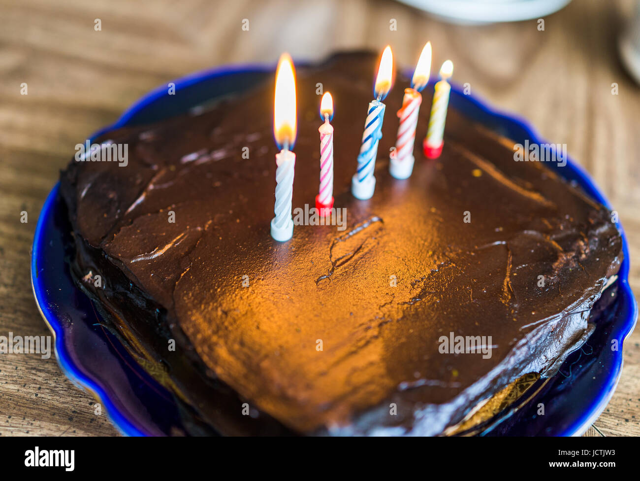Simple square small chocolate birthday cake with five colorful candles ...