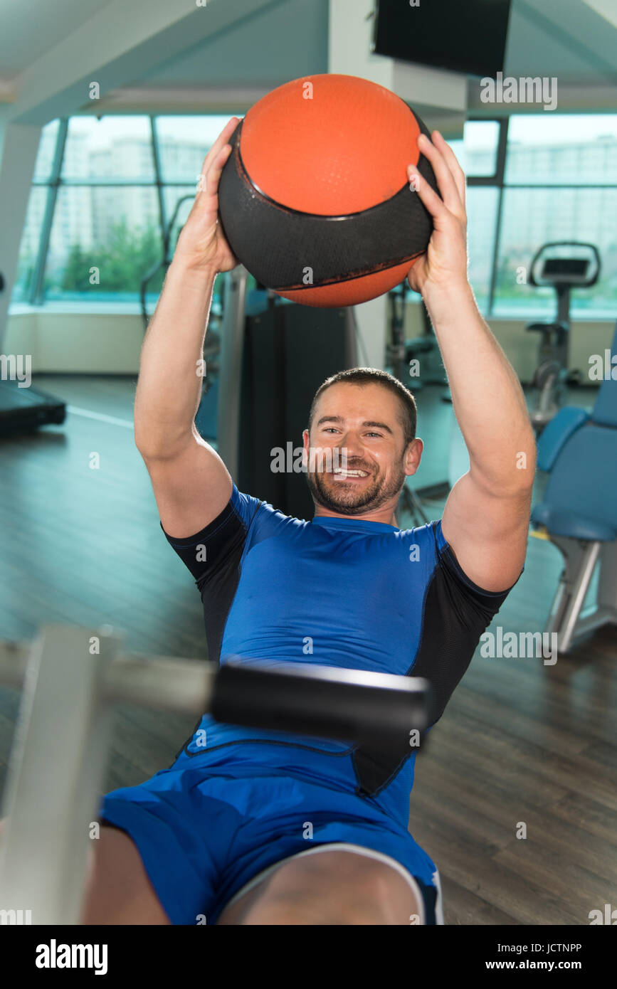Young Man Exercising Abs With Ball On Adjustable Bench In The Gym And ...