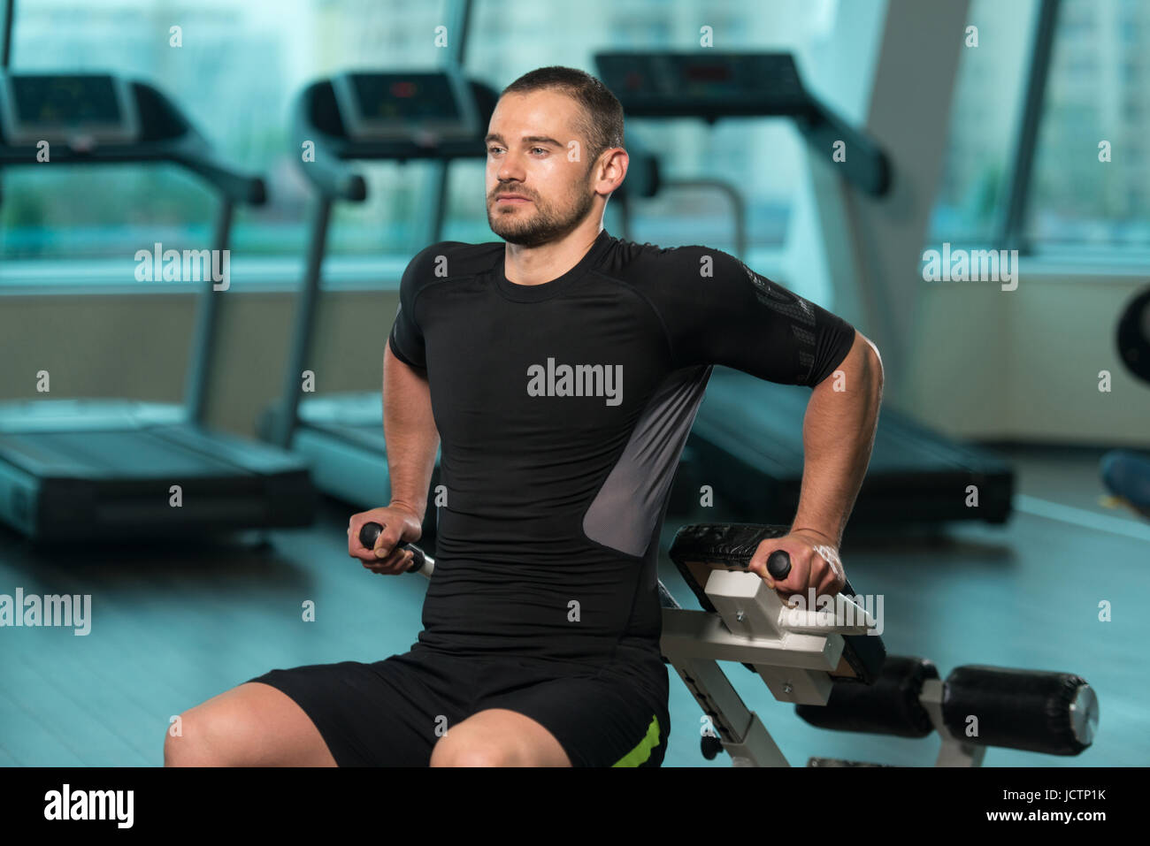 Young Man Exercising Triceps On Roman Chair In The Gym And Flexing ...