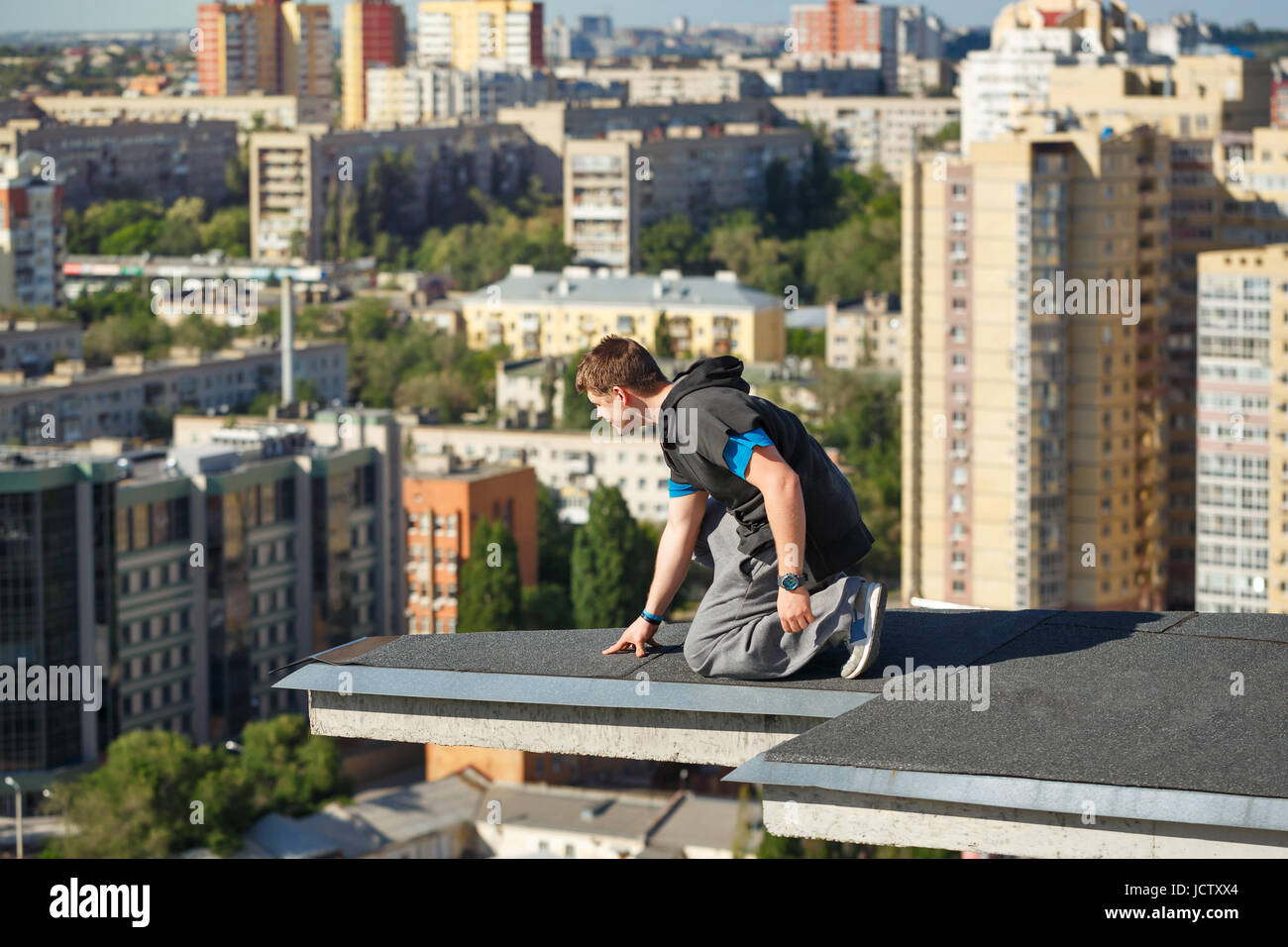 Roofer on the edge of the roof. A man looks down from a high-rise ...