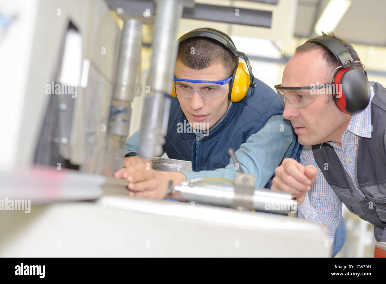 engineer and apprentice using automated milling machine Stock Photo - Alamy