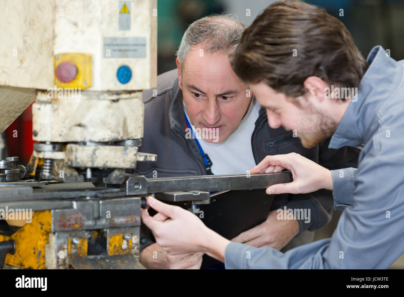 worker aligning metal under machine Stock Photo - Alamy