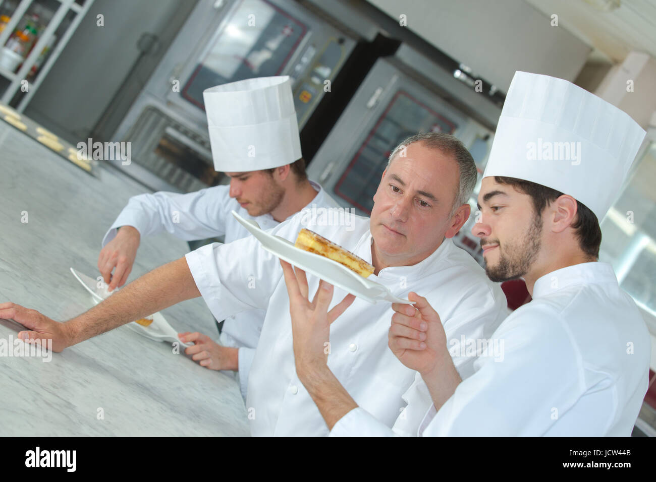 Pleased chef examining cake Stock Photo - Alamy