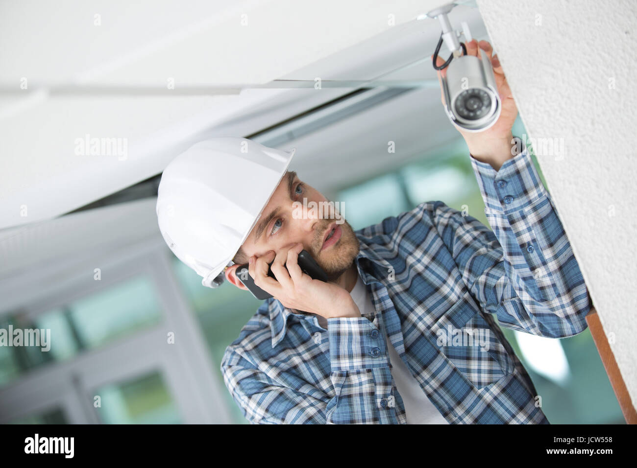 technician fixing cctv camera on wall and phoning for help Stock Photo ...