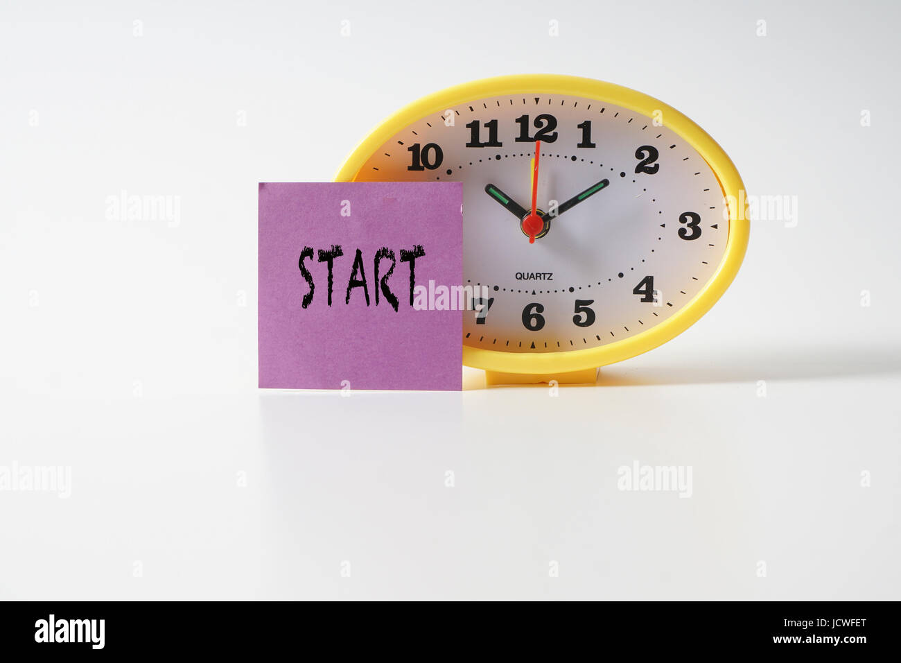 Yellow table clock with time management conceptual text on the note ...