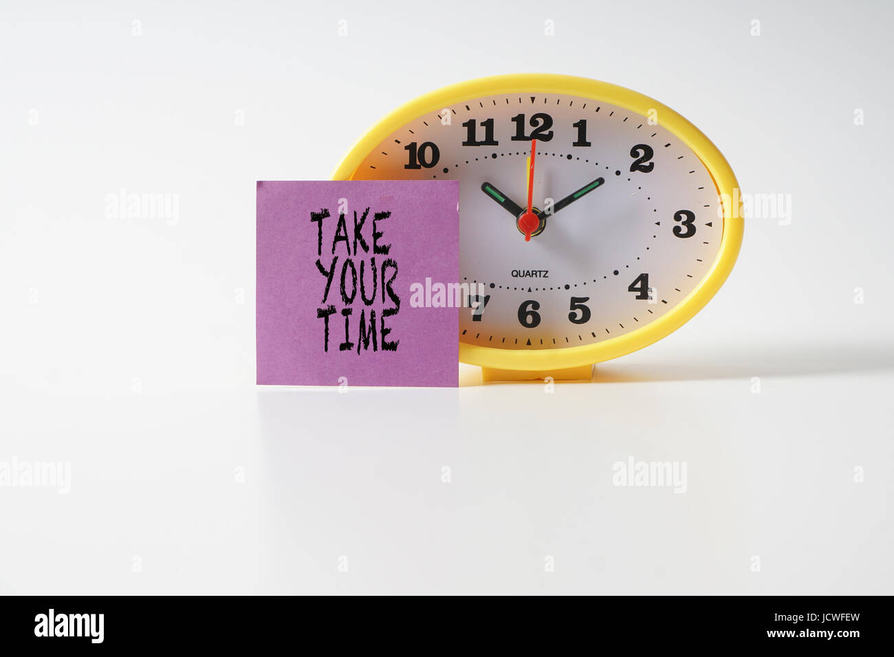Yellow table clock with time management conceptual text on the note ...