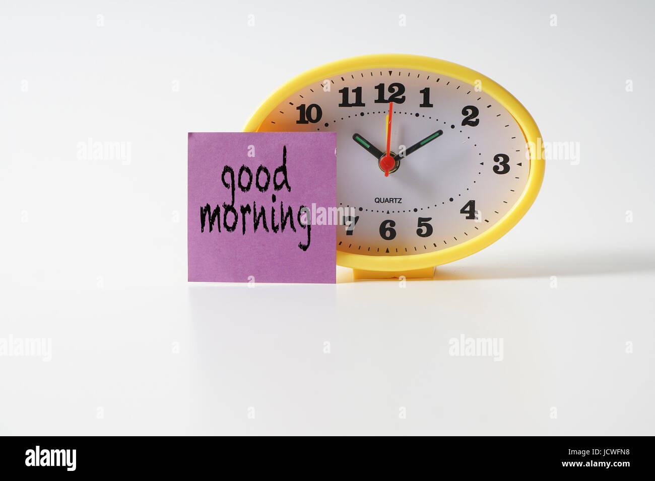 Yellow table clock with time management conceptual text on the note ...