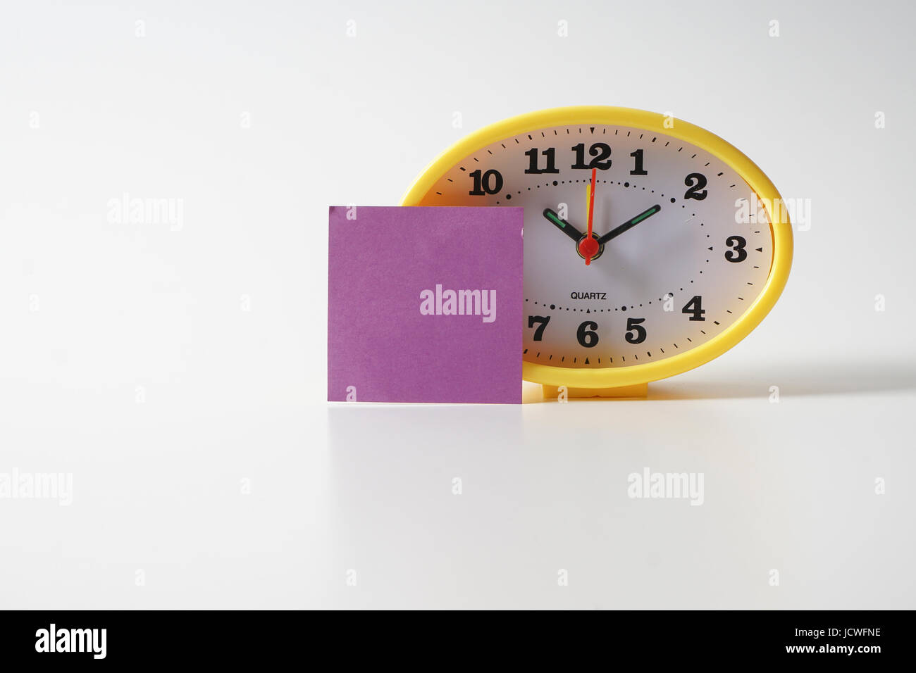 Yellow table clock with time management conceptual text on the note ...