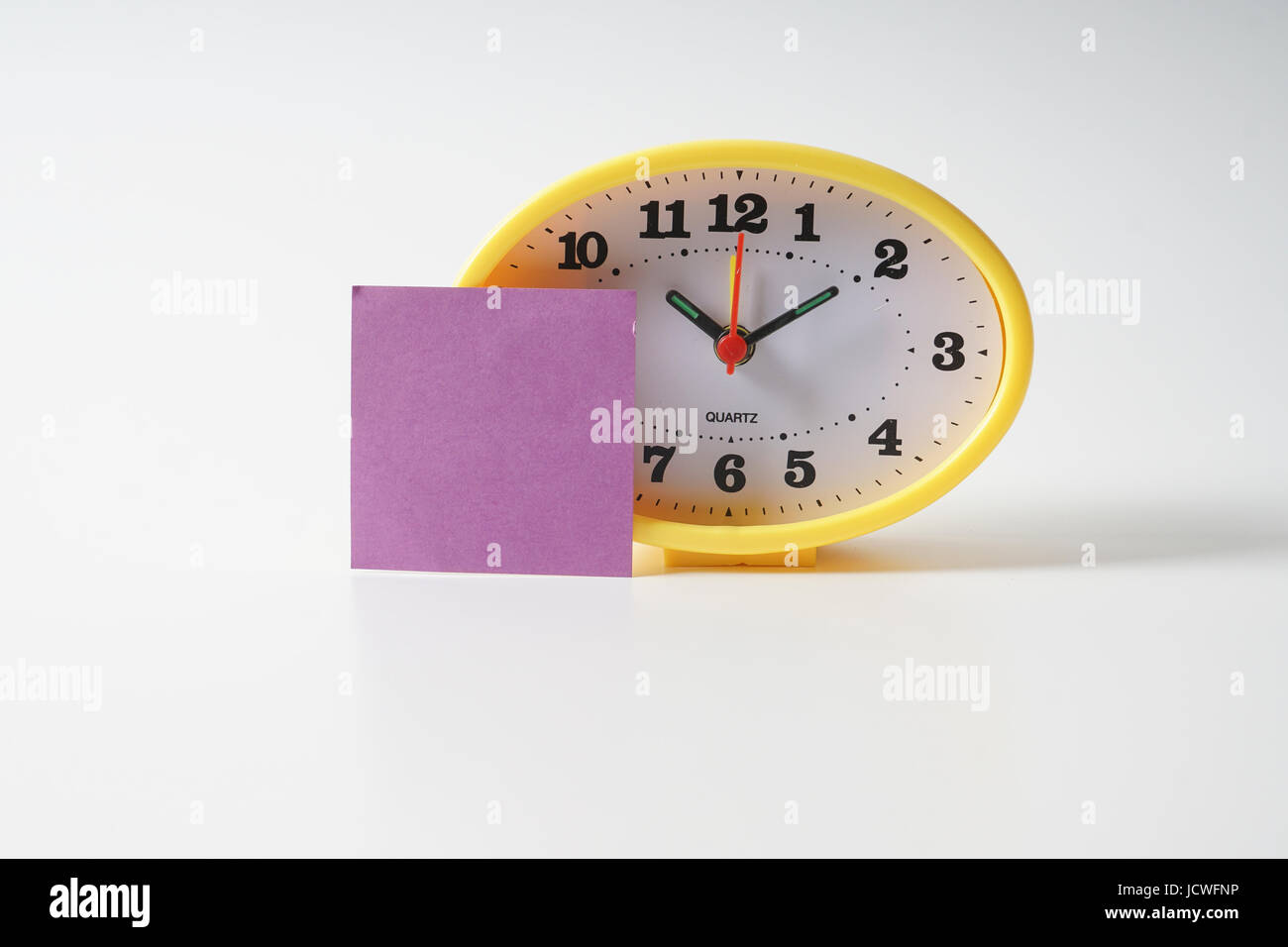Yellow table clock with time management conceptual text on the note ...