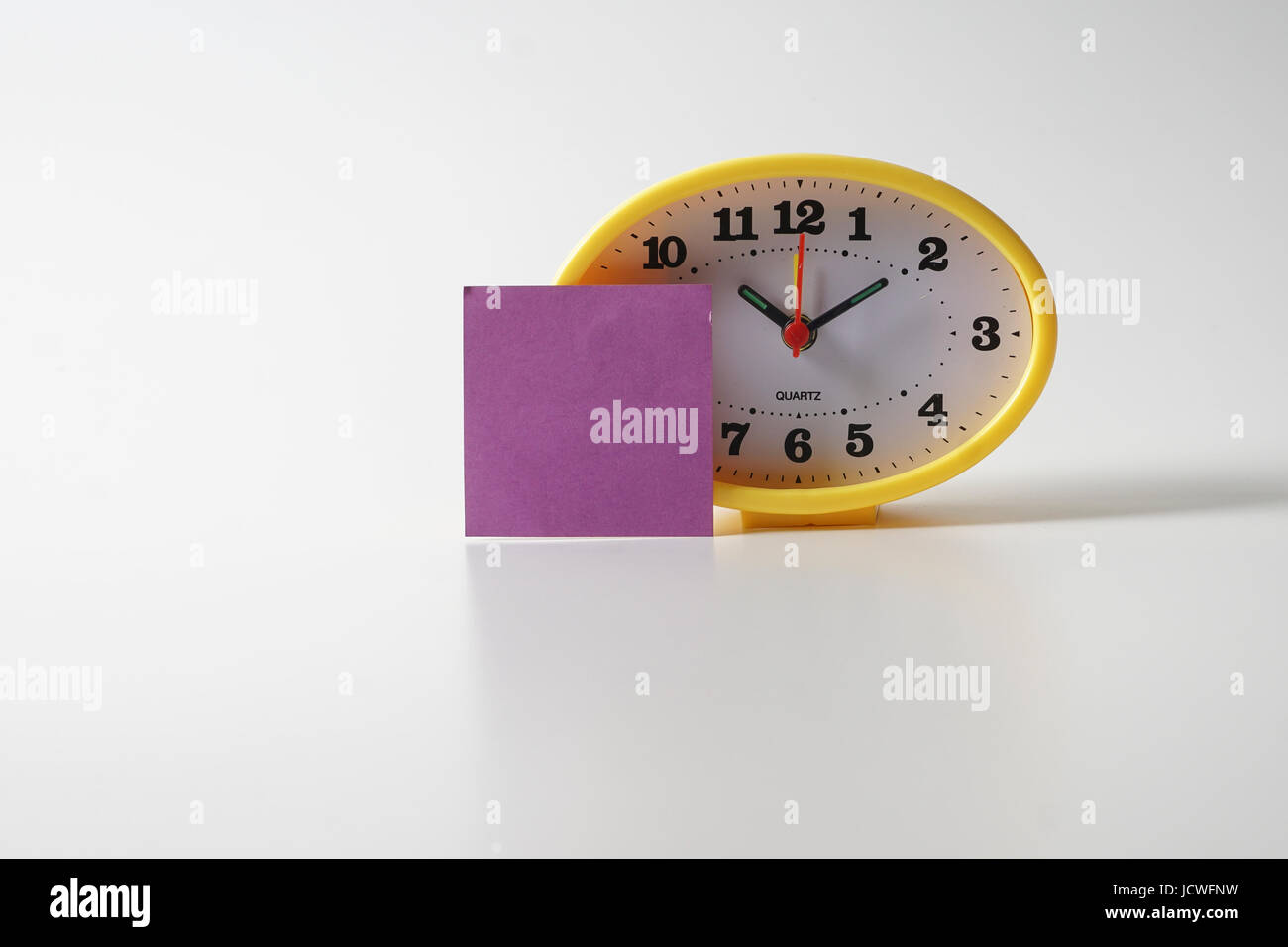 Yellow table clock with time management conceptual text on the note ...