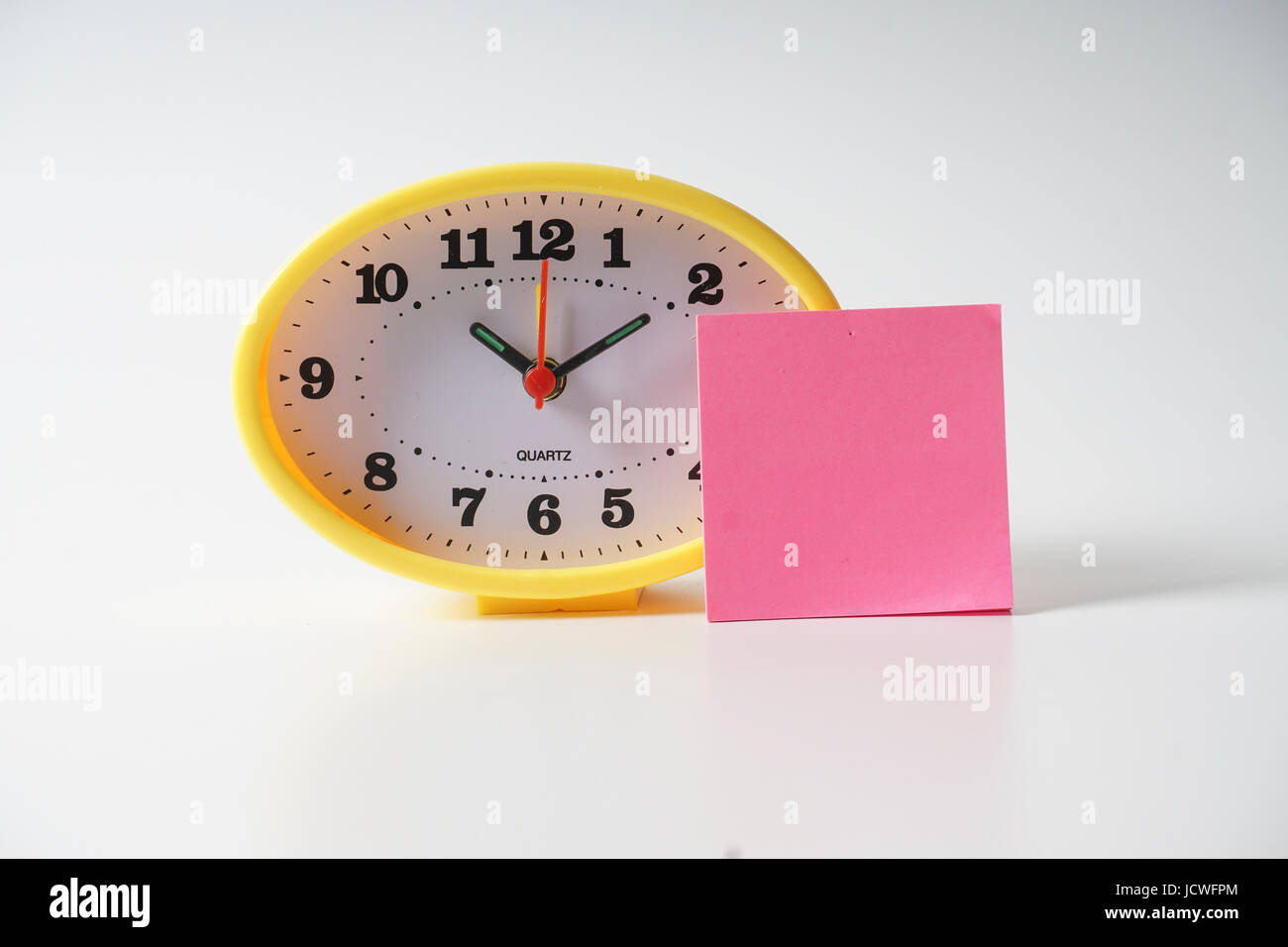 Yellow table clock with time management conceptual text on the note ...