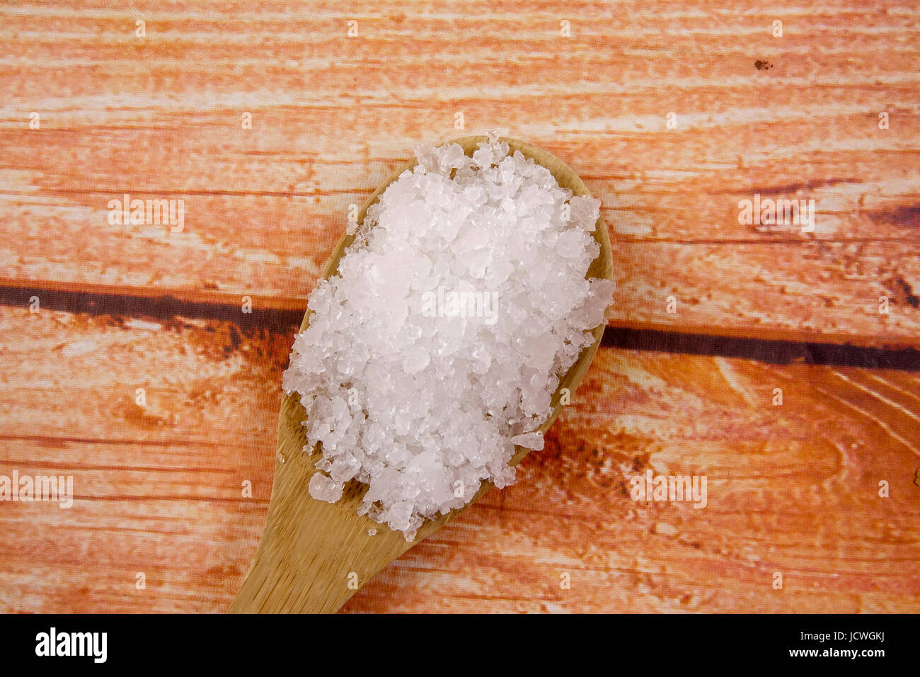 Sea salt in a wooden spoon. Also called bay salt or solar salt, is used ...