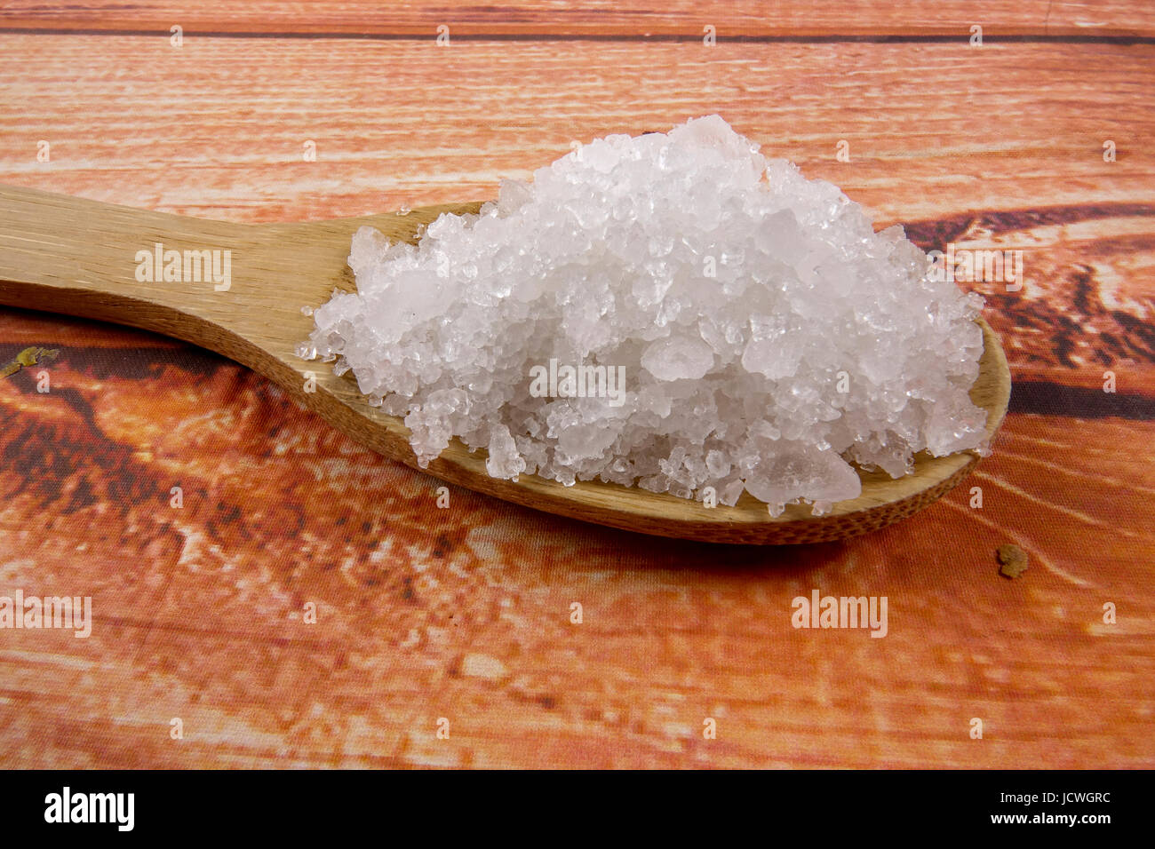 Sea salt in a wooden spoon. Also called bay salt or solar salt, is used ...