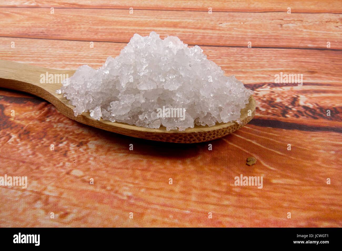 Sea salt in a wooden spoon. Also called bay salt or solar salt, is used ...