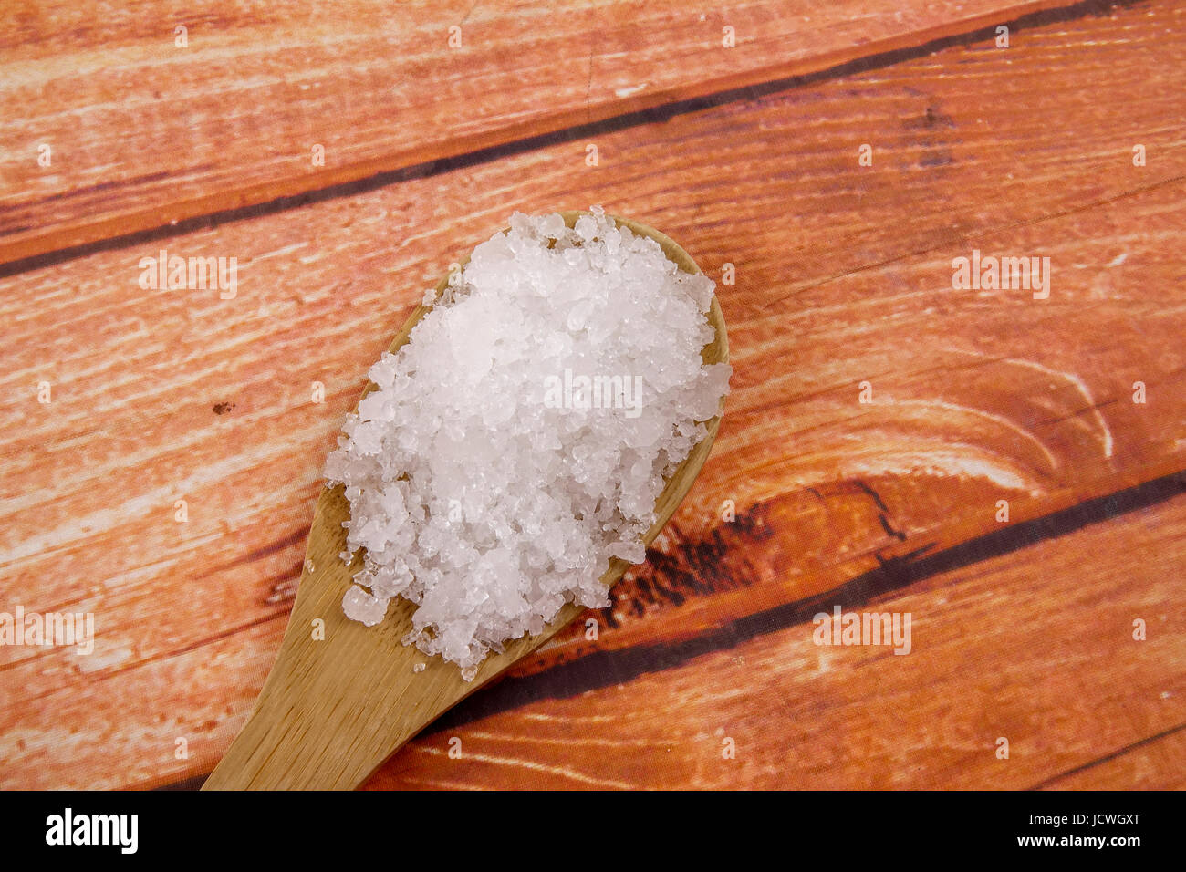 Sea salt in a wooden spoon. Also called bay salt or solar salt, is used ...