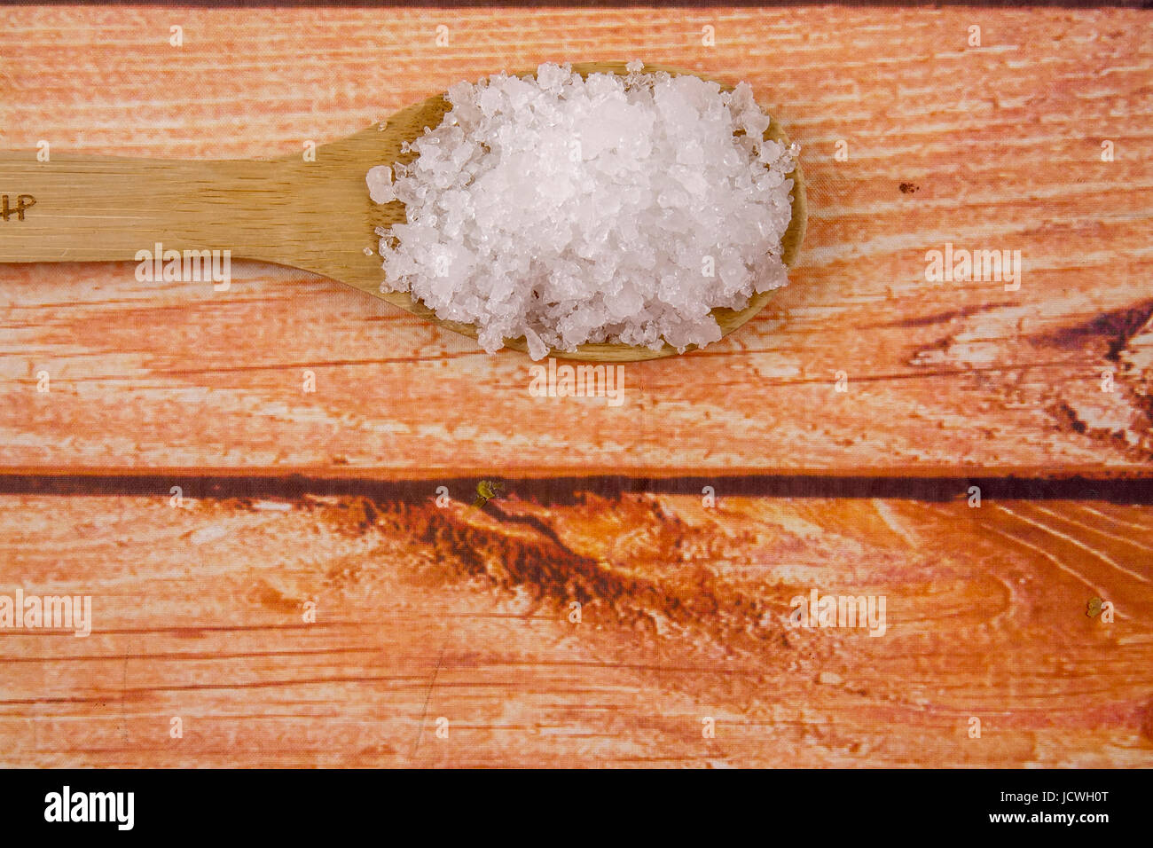 Sea salt in a wooden spoon. Also called bay salt or solar salt, is used ...