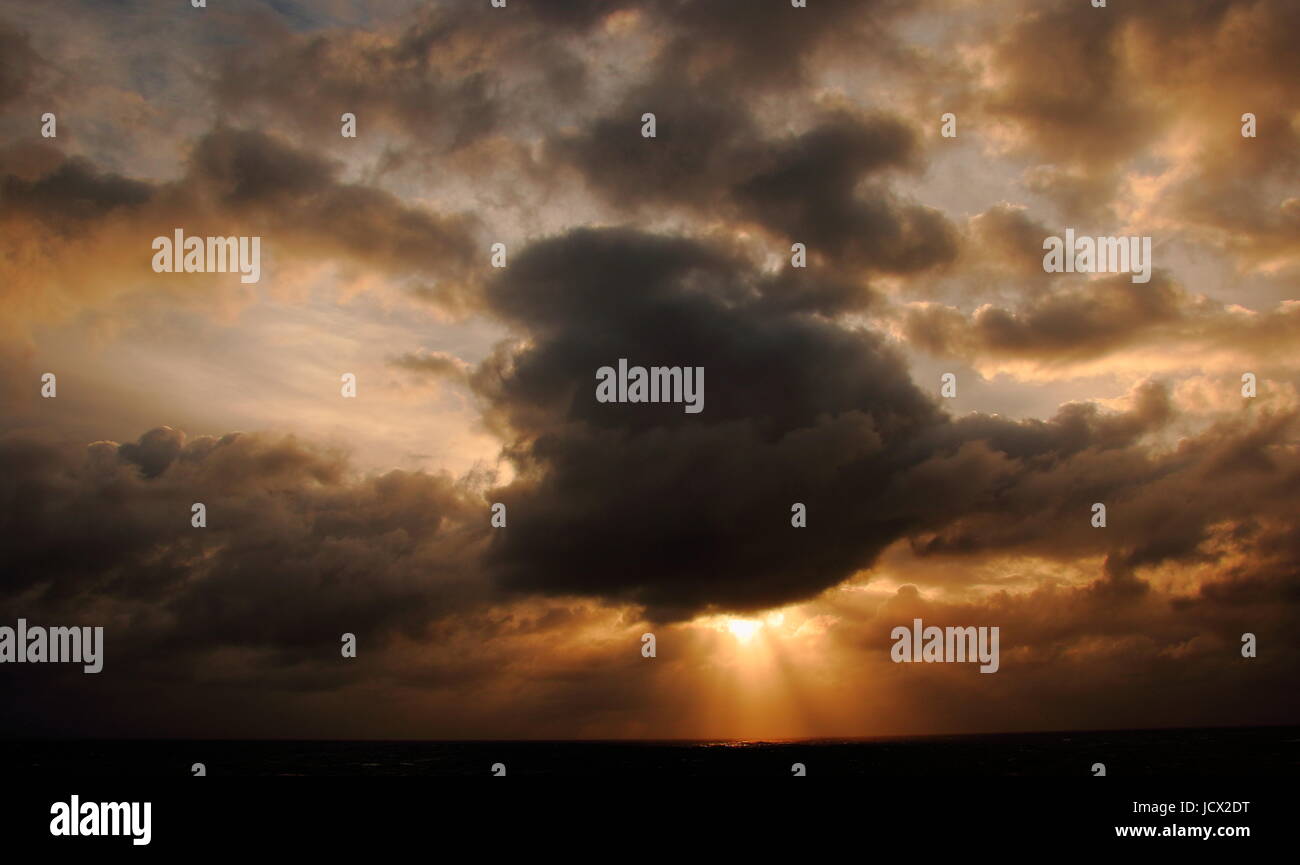Dramatic moody sunset over the sea with storm clouds and rays of ...