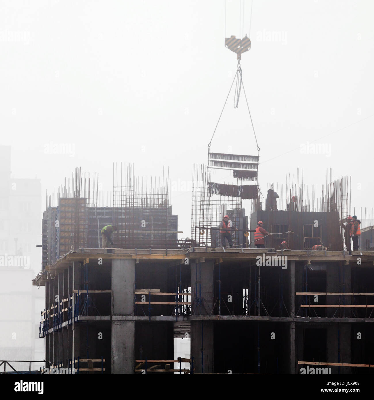A new residential building under construction in the morning mist. Iron ...