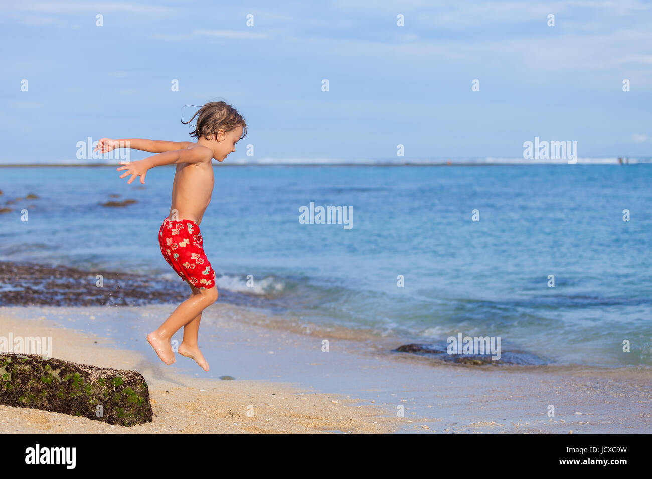 Portrait of little boy jumping on the beach at the day time Stock Photo ...
