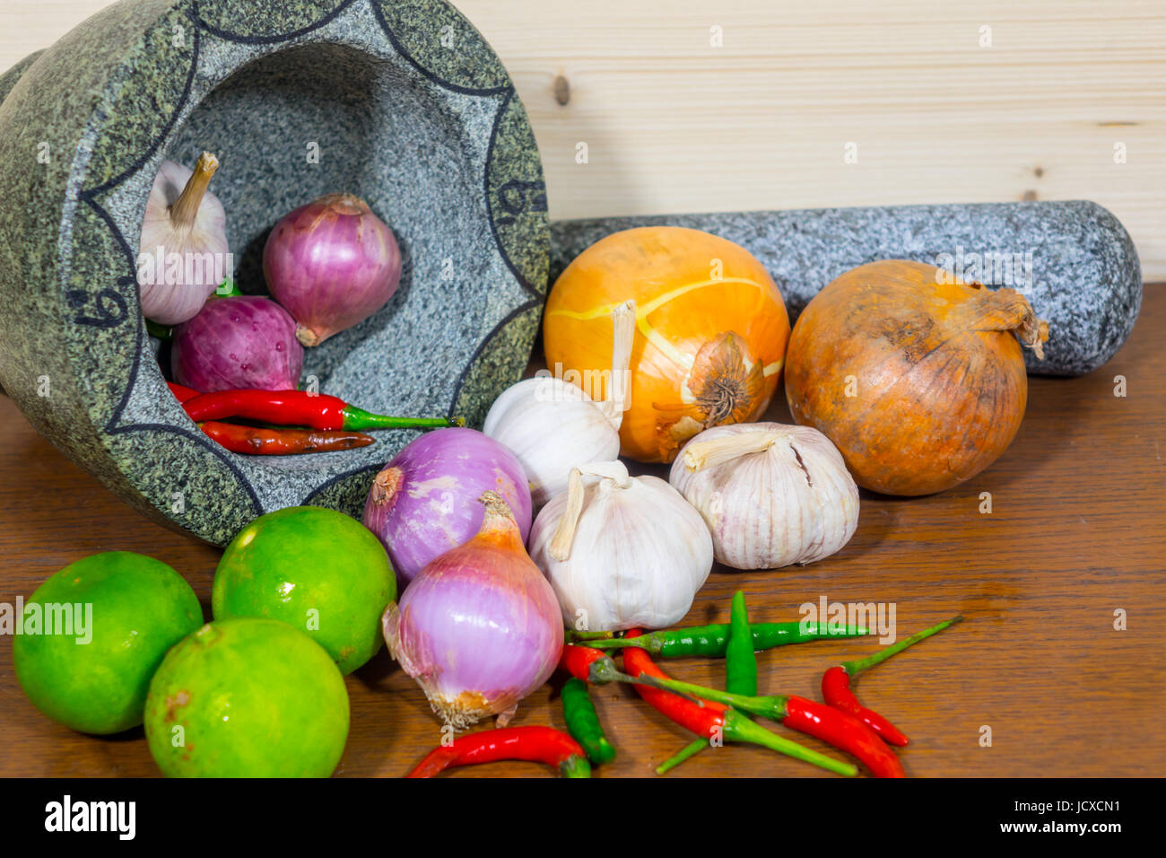 Mortar, lemon, pepper, onion and garlic, cooking on wooden background ...