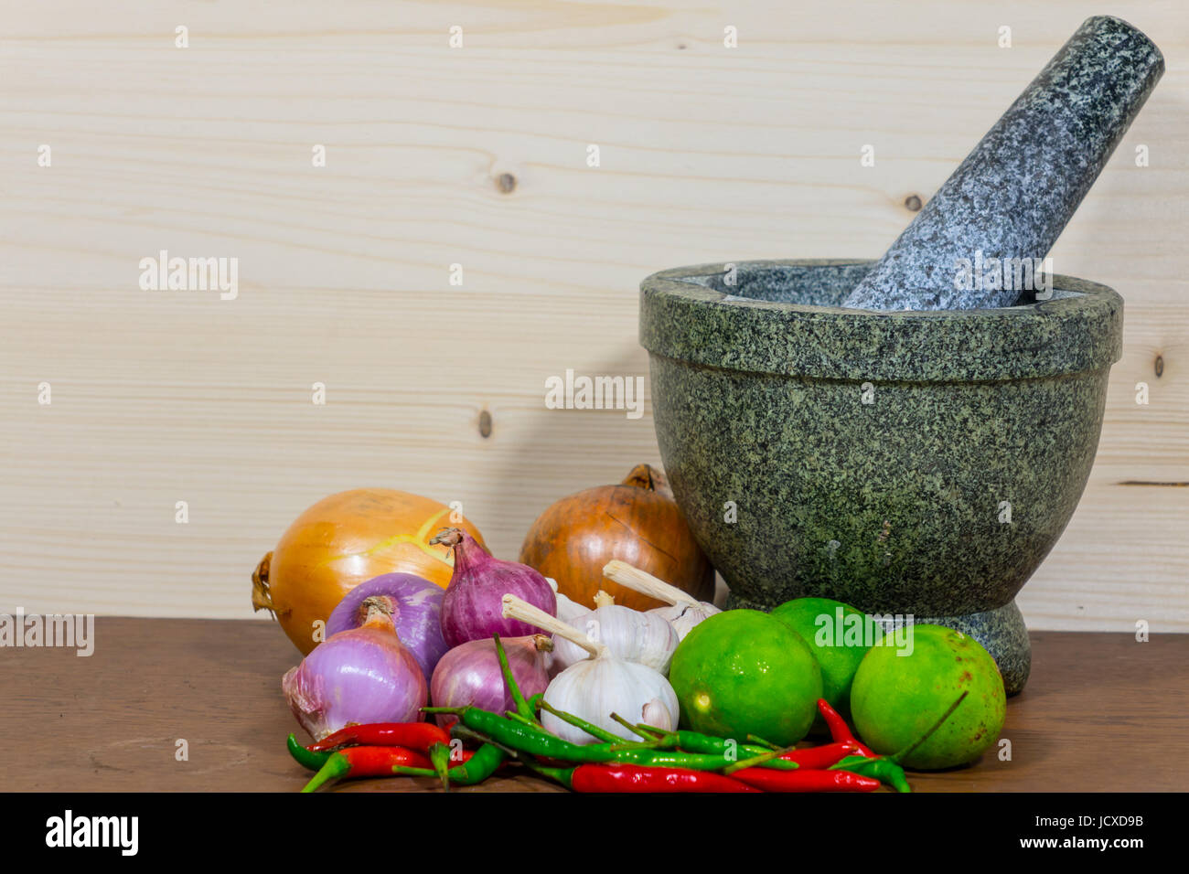 Mortar, lemon, pepper, onion and garlic, cooking on wooden background ...