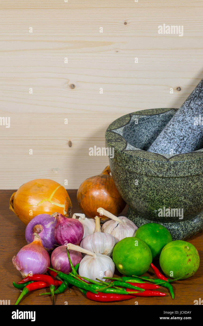 Mortar, lemon, pepper, onion and garlic, cooking on wooden background ...