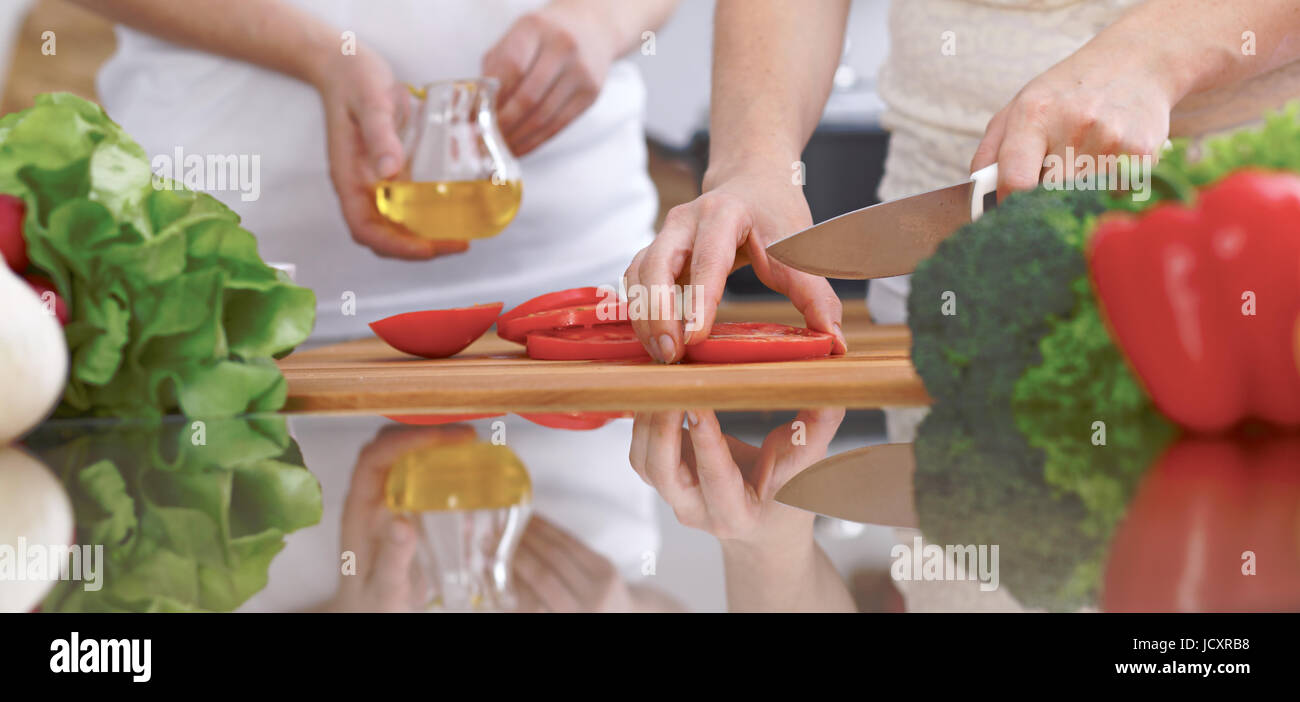 Close-up of four human hands are cooking in a kitchen. Friends having ...