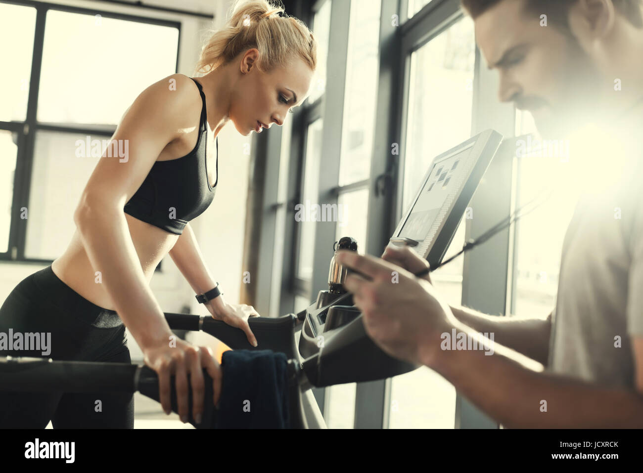 Blonde woman workout on treadmill and trainer with timer, side view ...