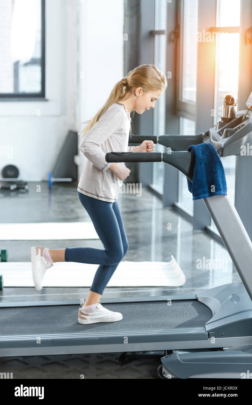 Blonde girl workout on treadmill, side view Stock Photo - Alamy