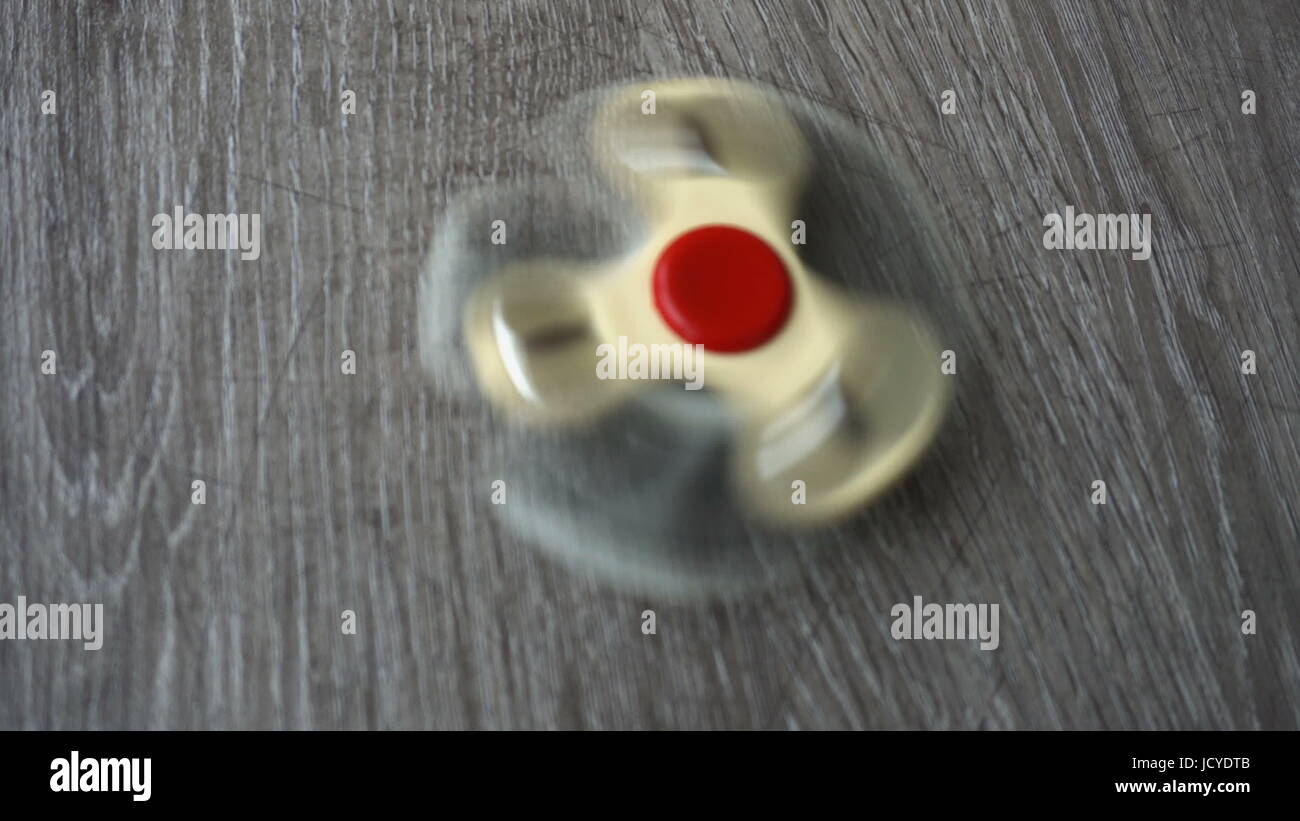 two white hand spinner spinning on grey background or fidget spinners ...