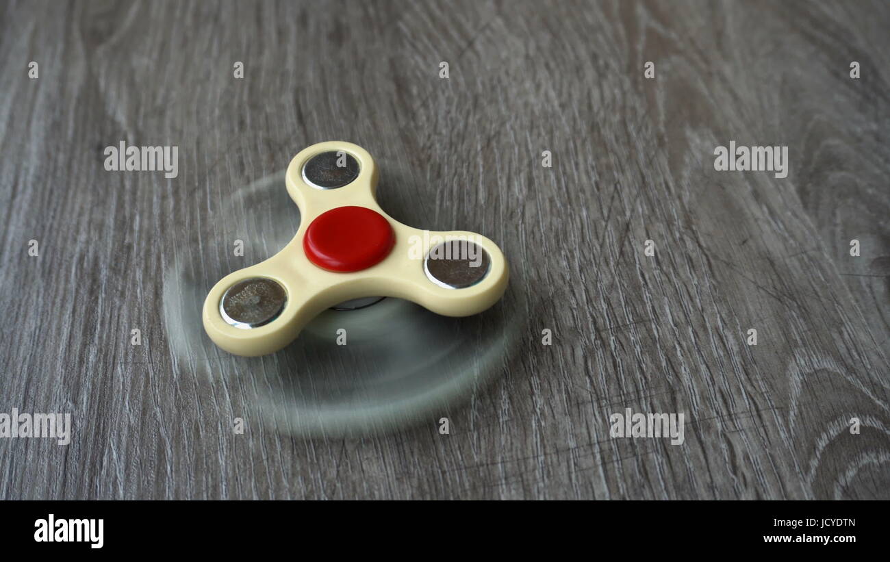 two white hand spinner spinning on grey background or fidget spinners ...