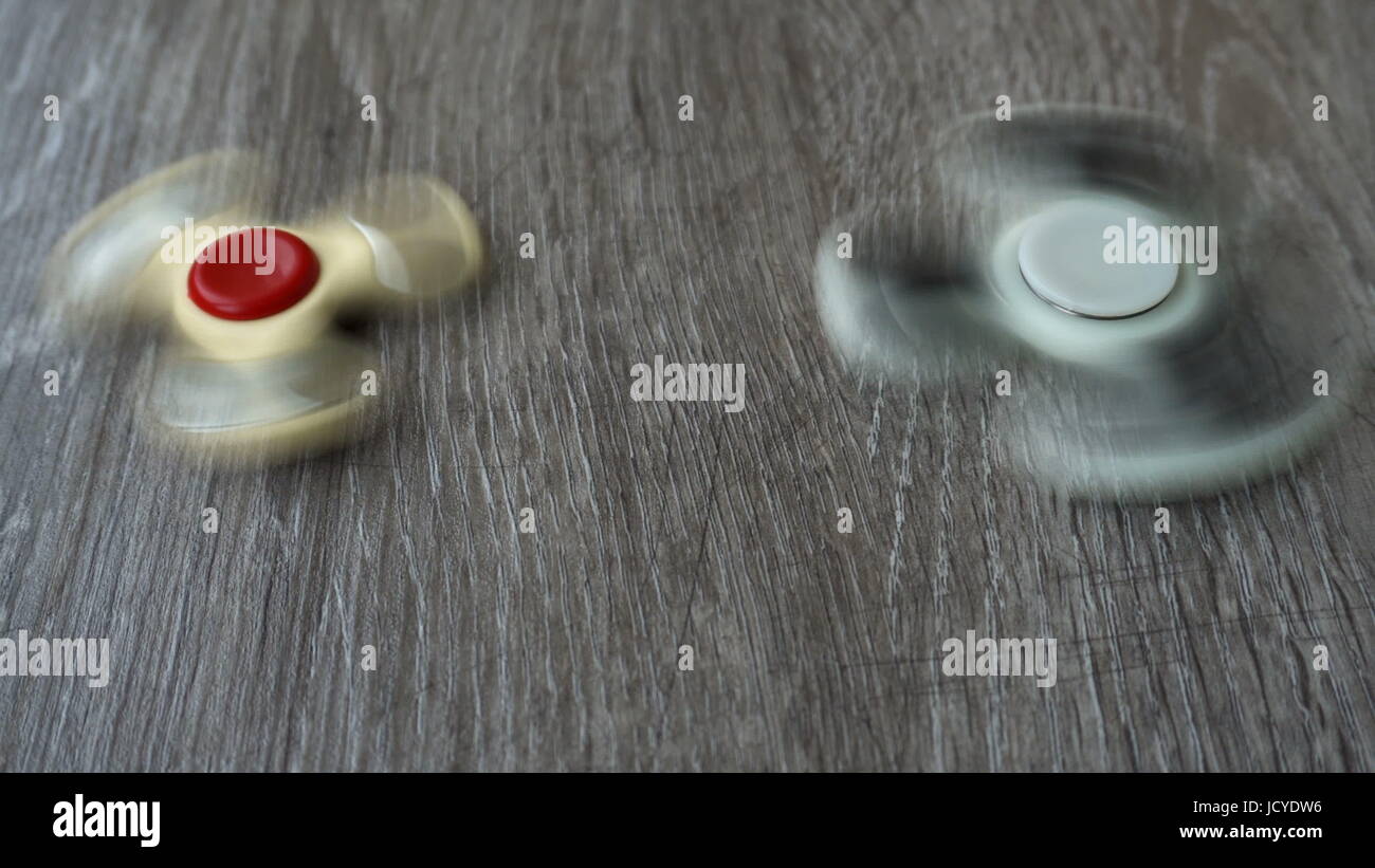 two white hand spinner spinning on grey background or fidget spinners ...