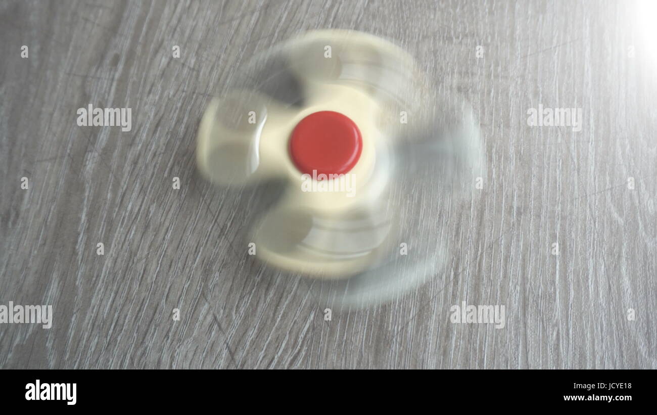 two white hand spinner spinning on grey background or fidget spinners ...