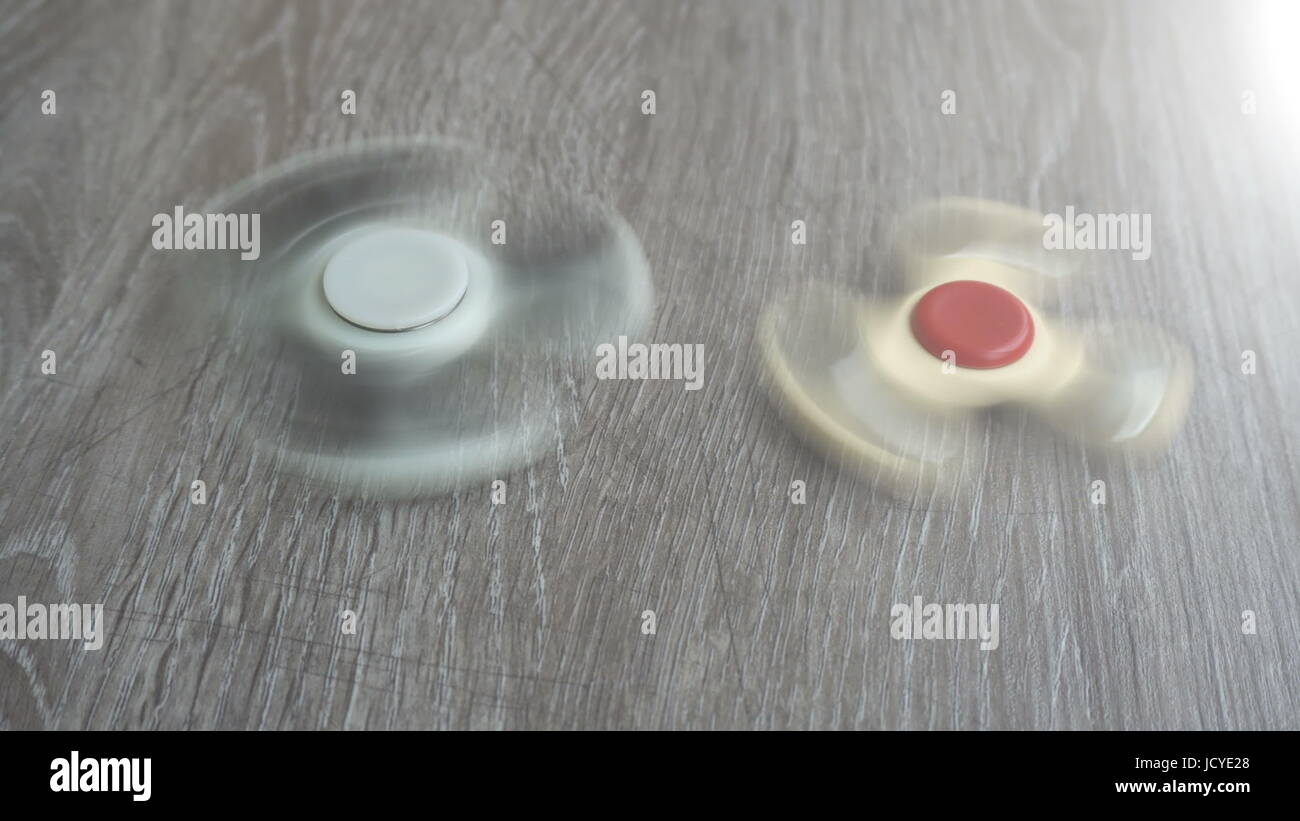 two white hand spinner spinning on grey background or fidget spinners ...