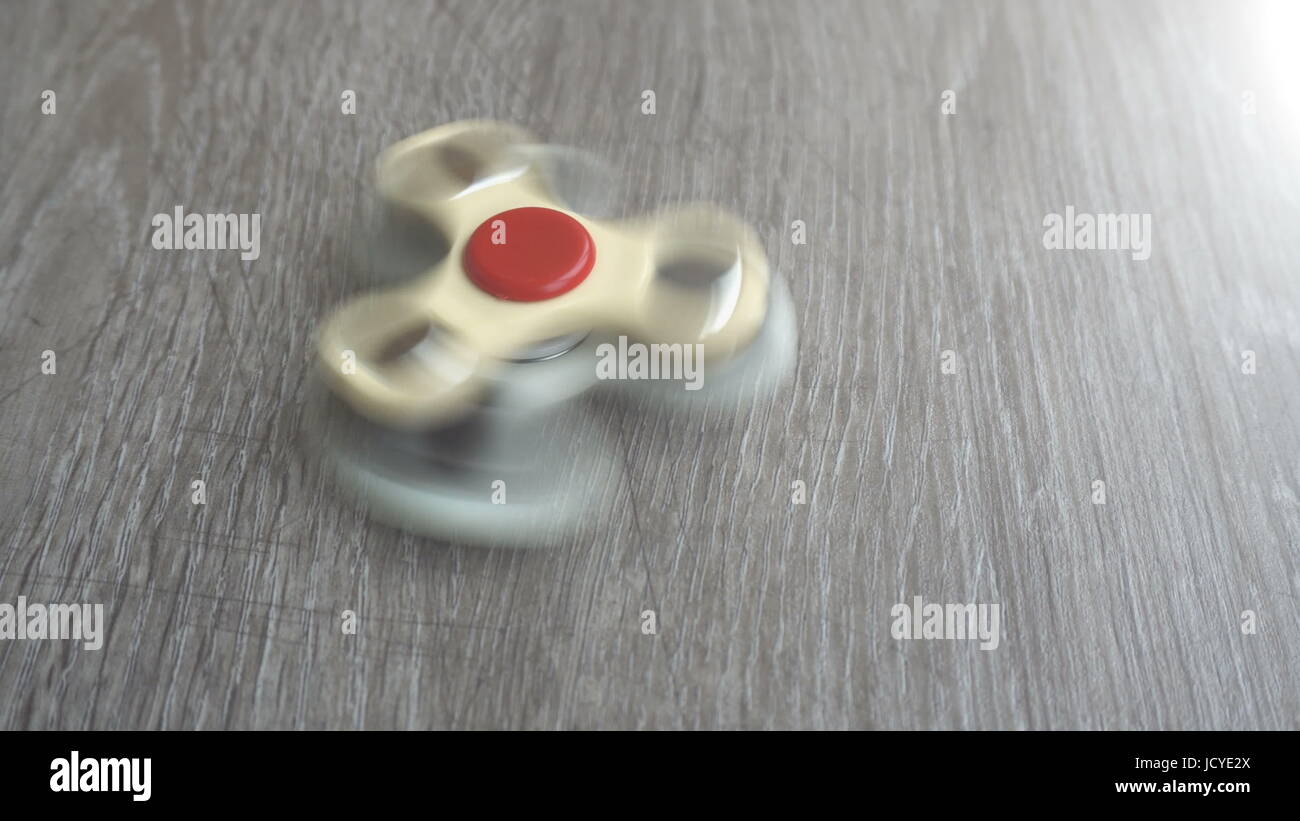 two white hand spinner spinning on grey background or fidget spinners ...