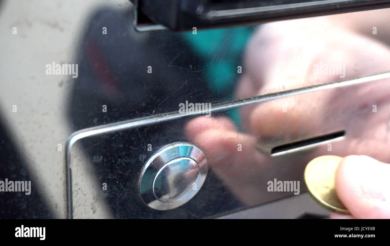 Customer inserts coin into money slot of vintage vending soda machine ...