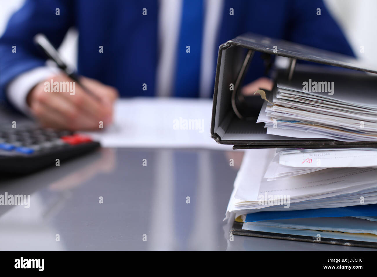 Binders with papers are waiting to be processed with businessman back ...