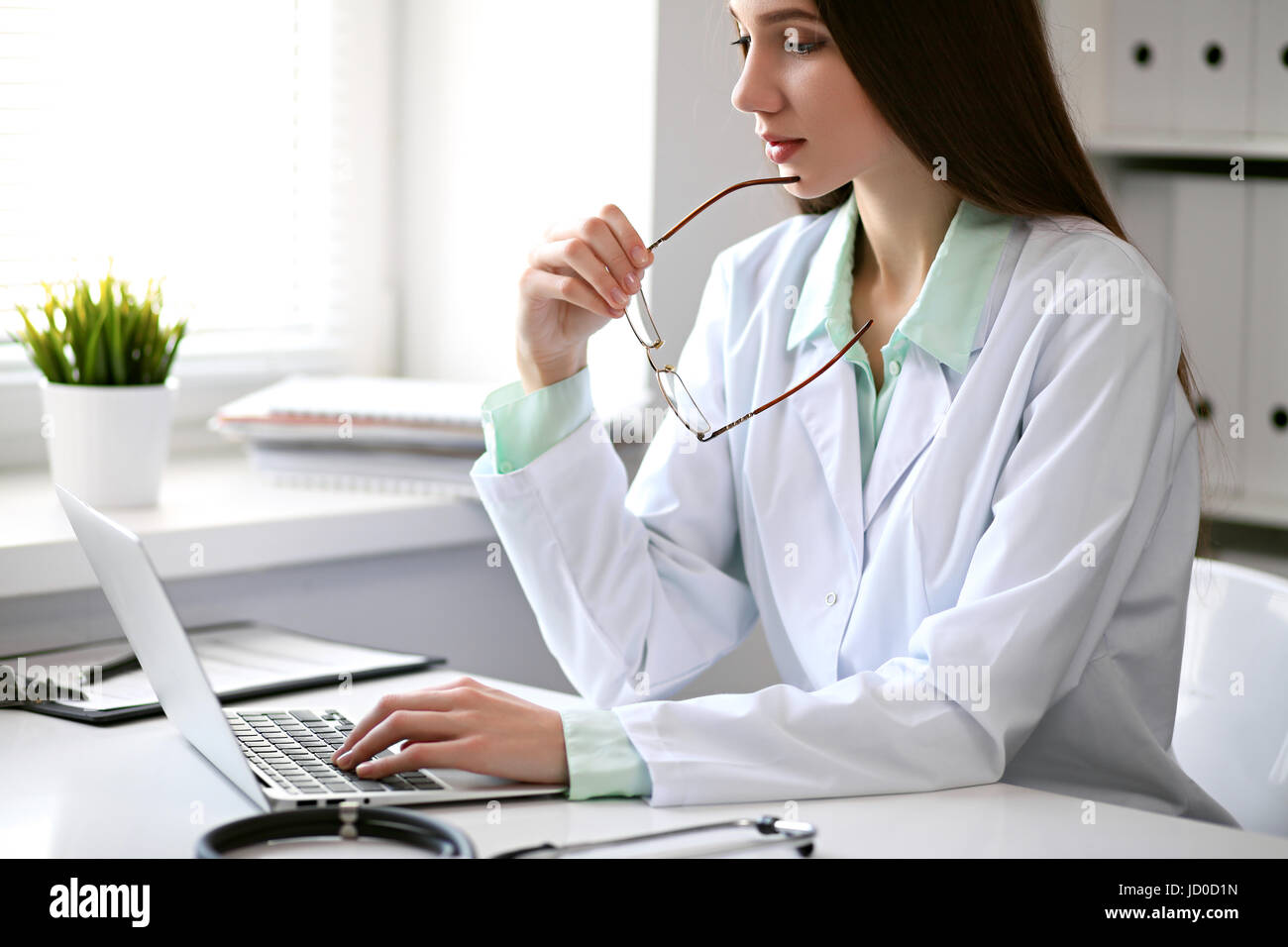 Female doctor brunette sitting at the table near the window in hospital ...