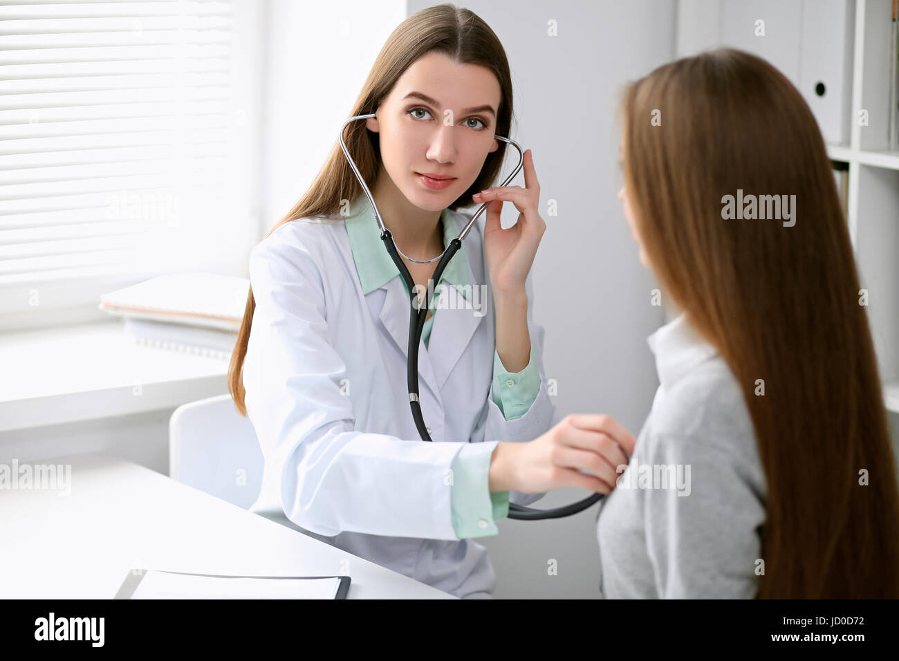 Doctor and patient sitting at the desk near the window in hospital ...