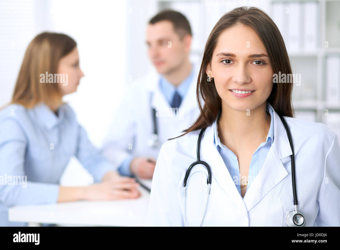 Young beautiful female doctor smiling on the background with patient in ...