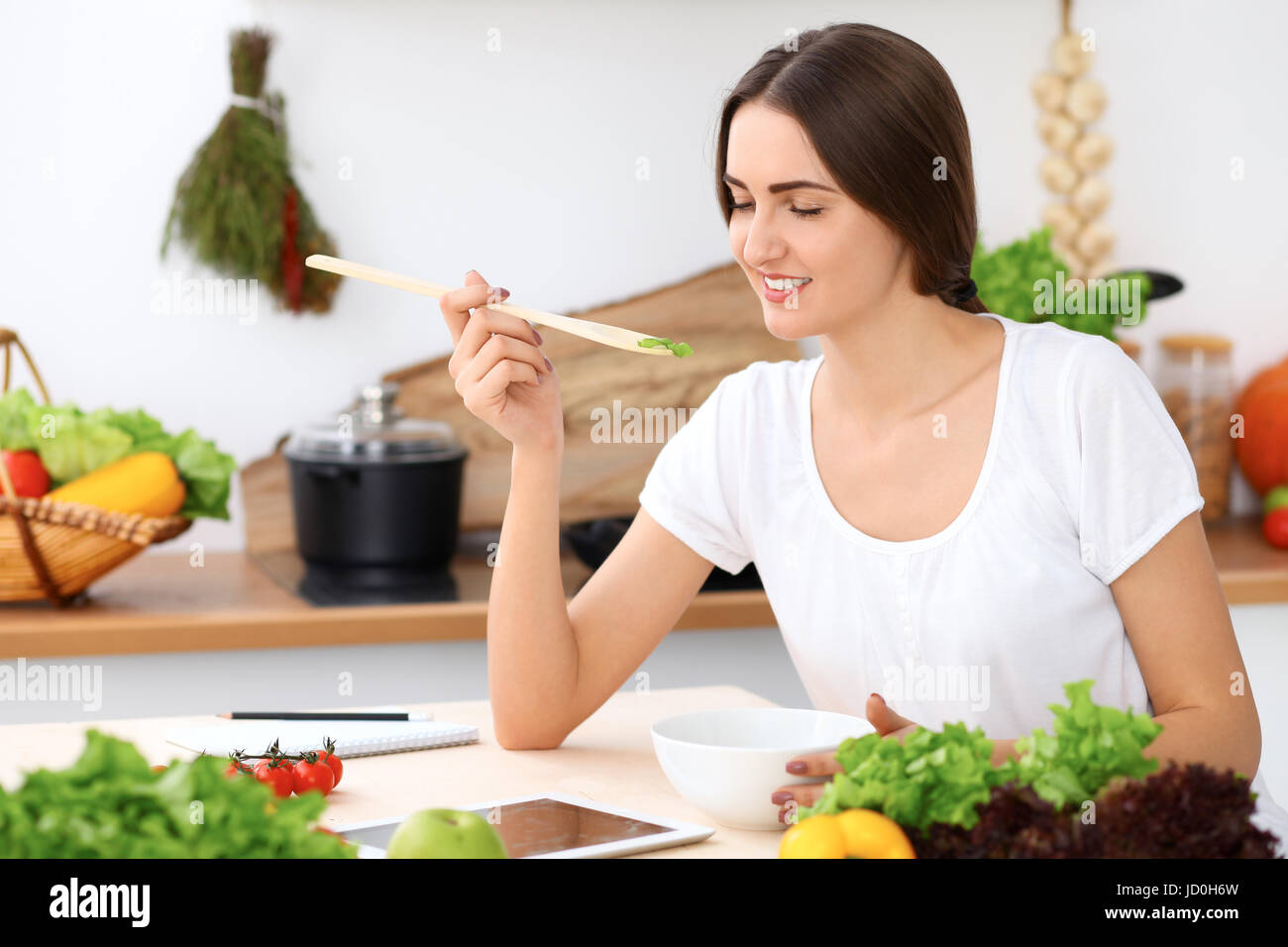 Beautiful Hispanic woman is cooking in the kitchen. Housewife is ...