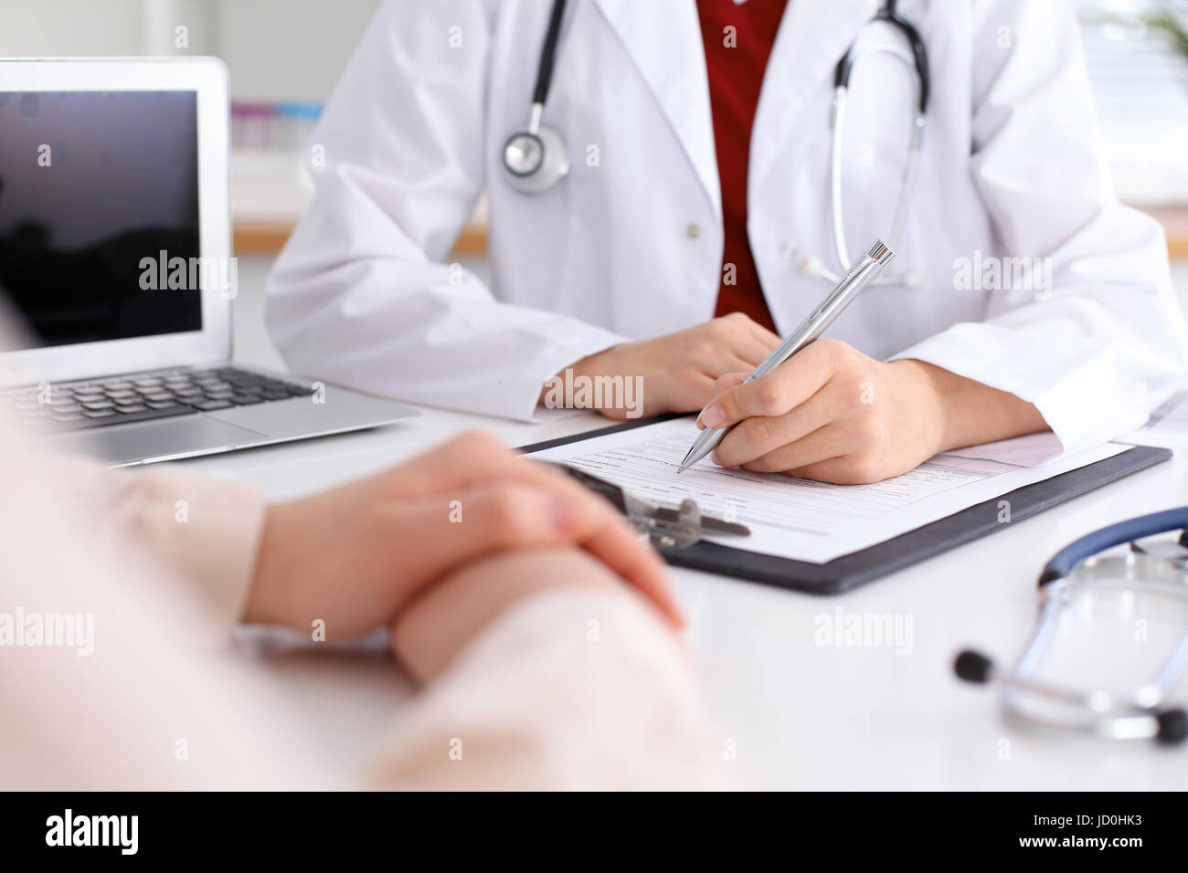 Close up of a female doctor filling up an application form while ...