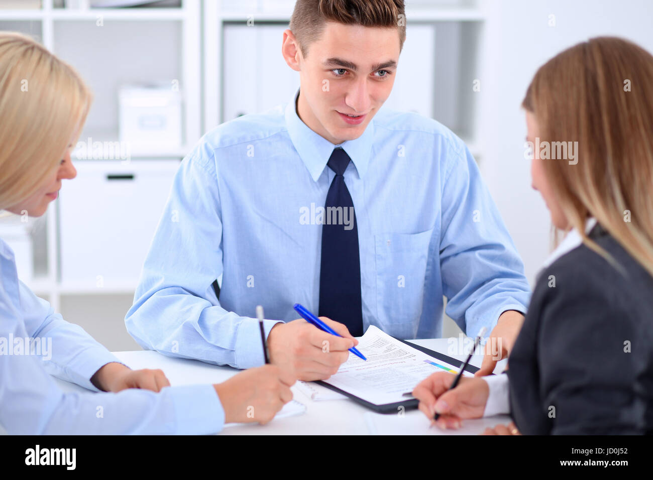 Business people sitting in office and working, focus on young man ...